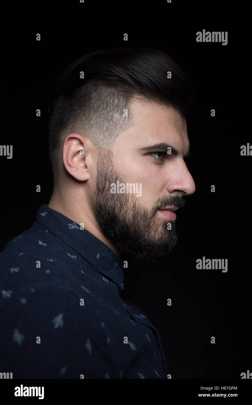 low key portrait of young handsome man in dark shirt isolated on black ...