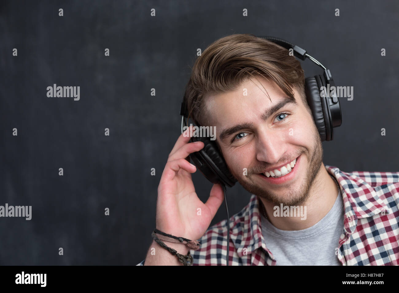 Portrait of confident young DJ with stylish haircut and headphones on ...