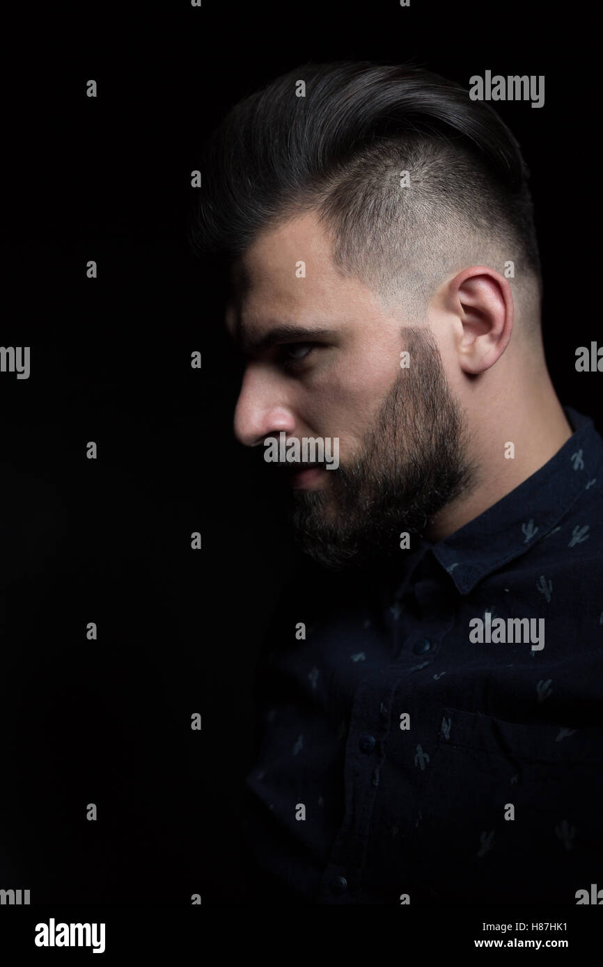 low key portrait of young handsome man in dark shirt isolated on black ...