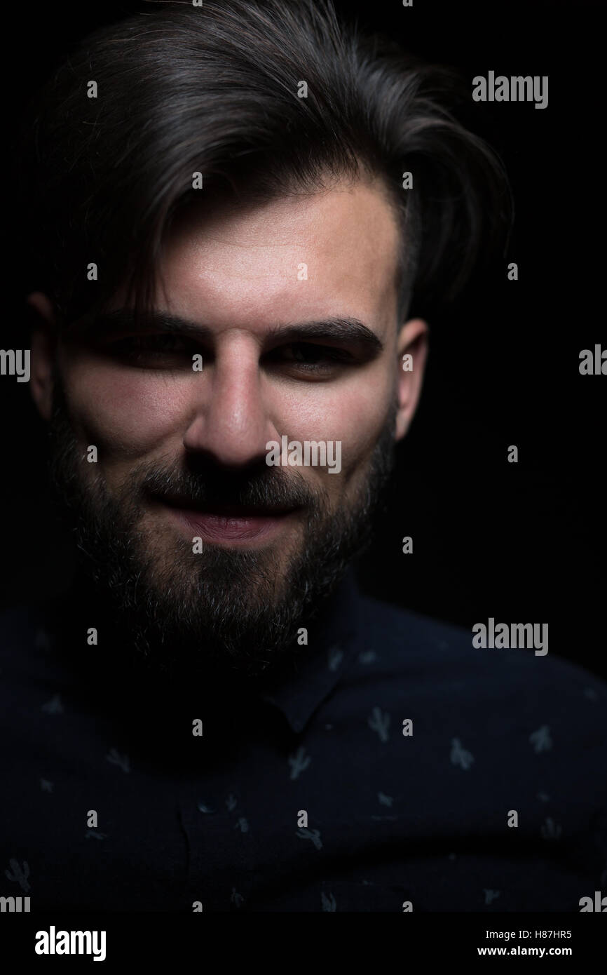 low key portrait of young handsome man in dark shirt isolated on black ...