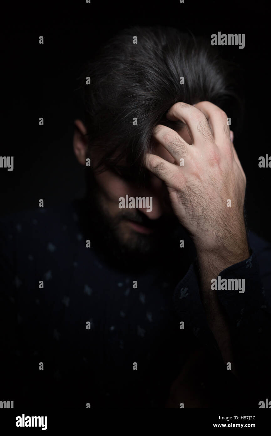 low key portrait of young handsome man in dark shirt isolated on black ...