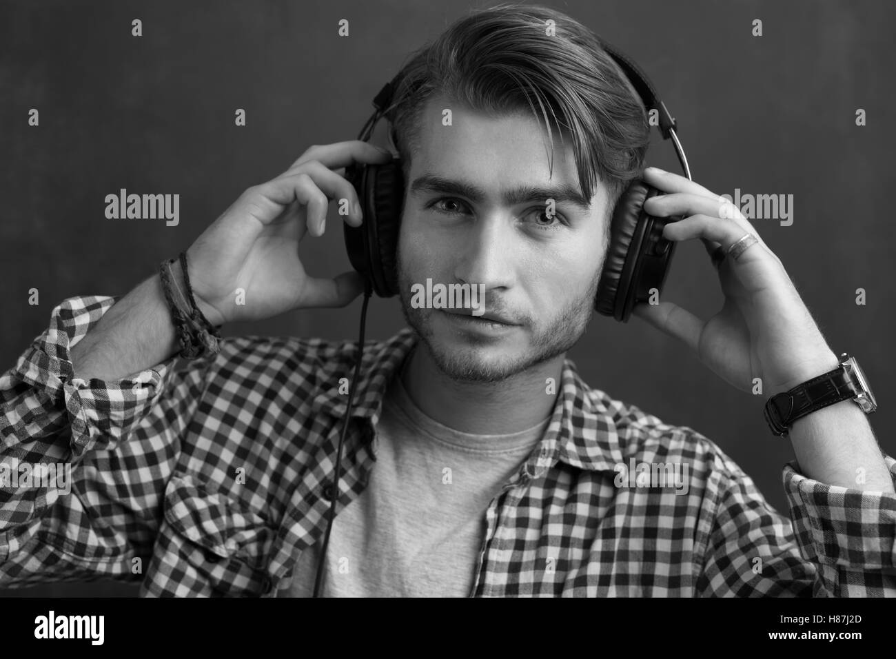 Portrait of confident young DJ with stylish haircut and headphones on ...