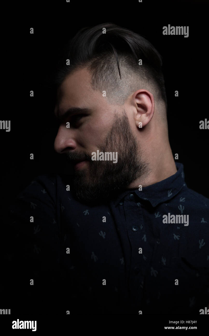 low key portrait of young handsome man in dark shirt isolated on black ...