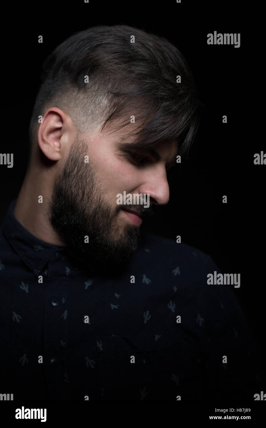 low key portrait of young handsome man in dark shirt isolated on black ...