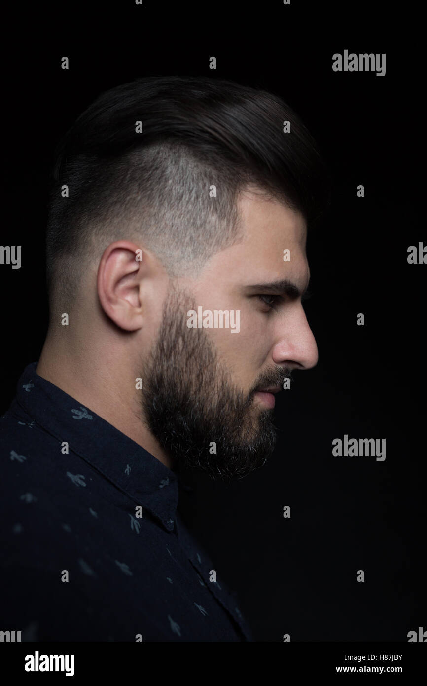 low key portrait of young handsome man in dark shirt isolated on black ...
