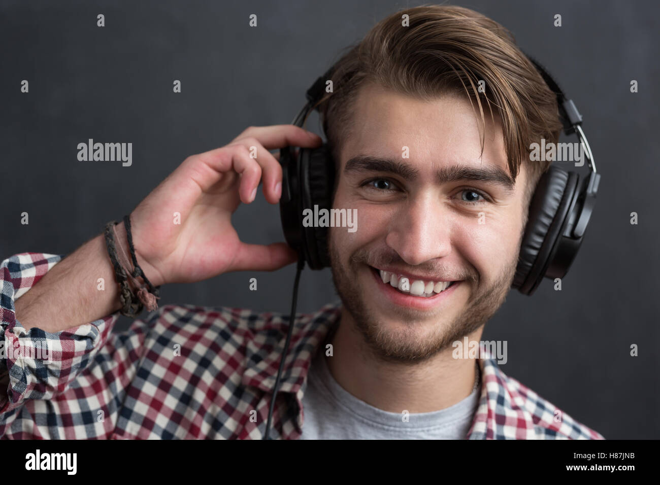 Portrait of confident young DJ with stylish haircut and headphones on ...