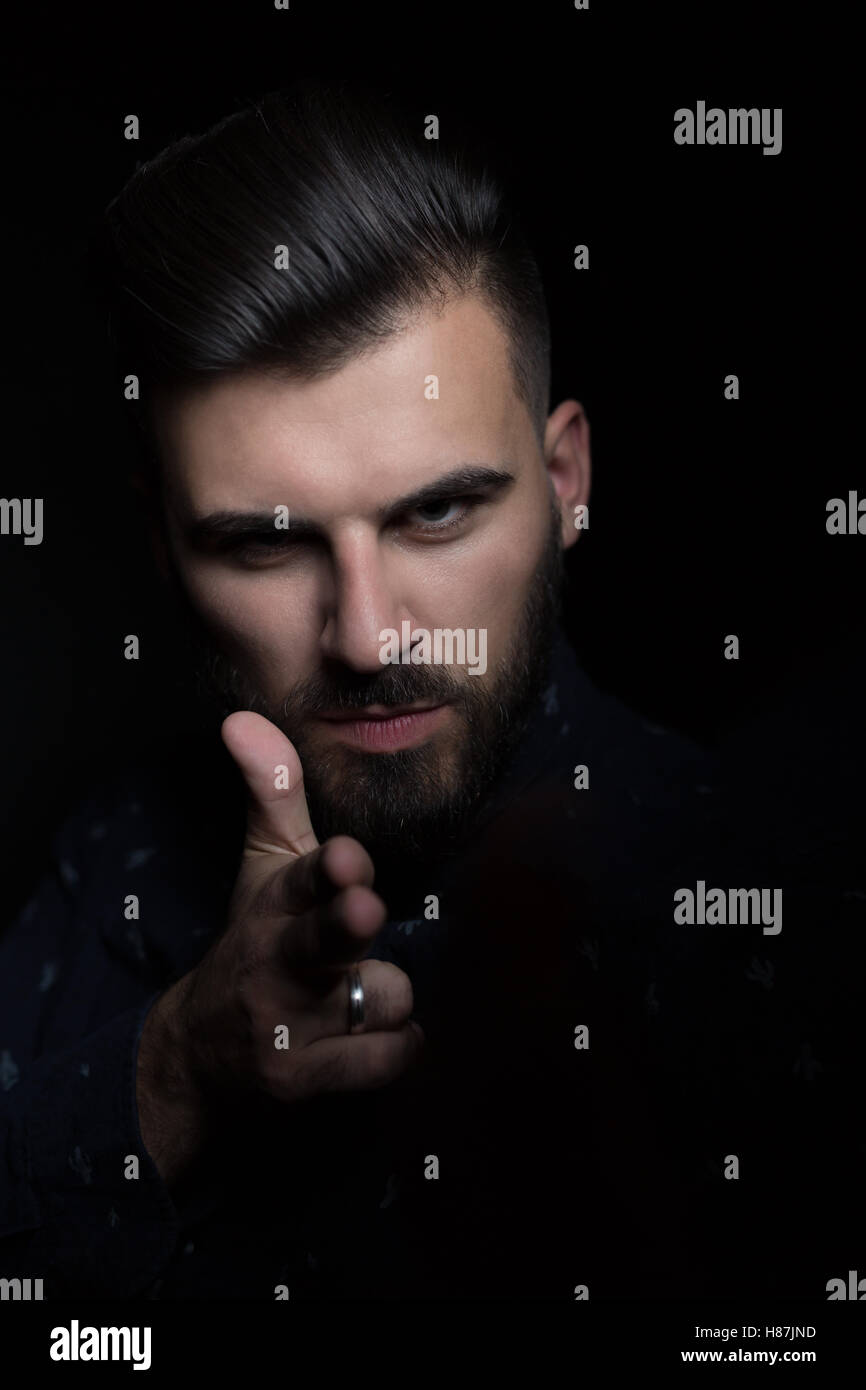 low key portrait of young handsome man in dark shirt isolated on black ...