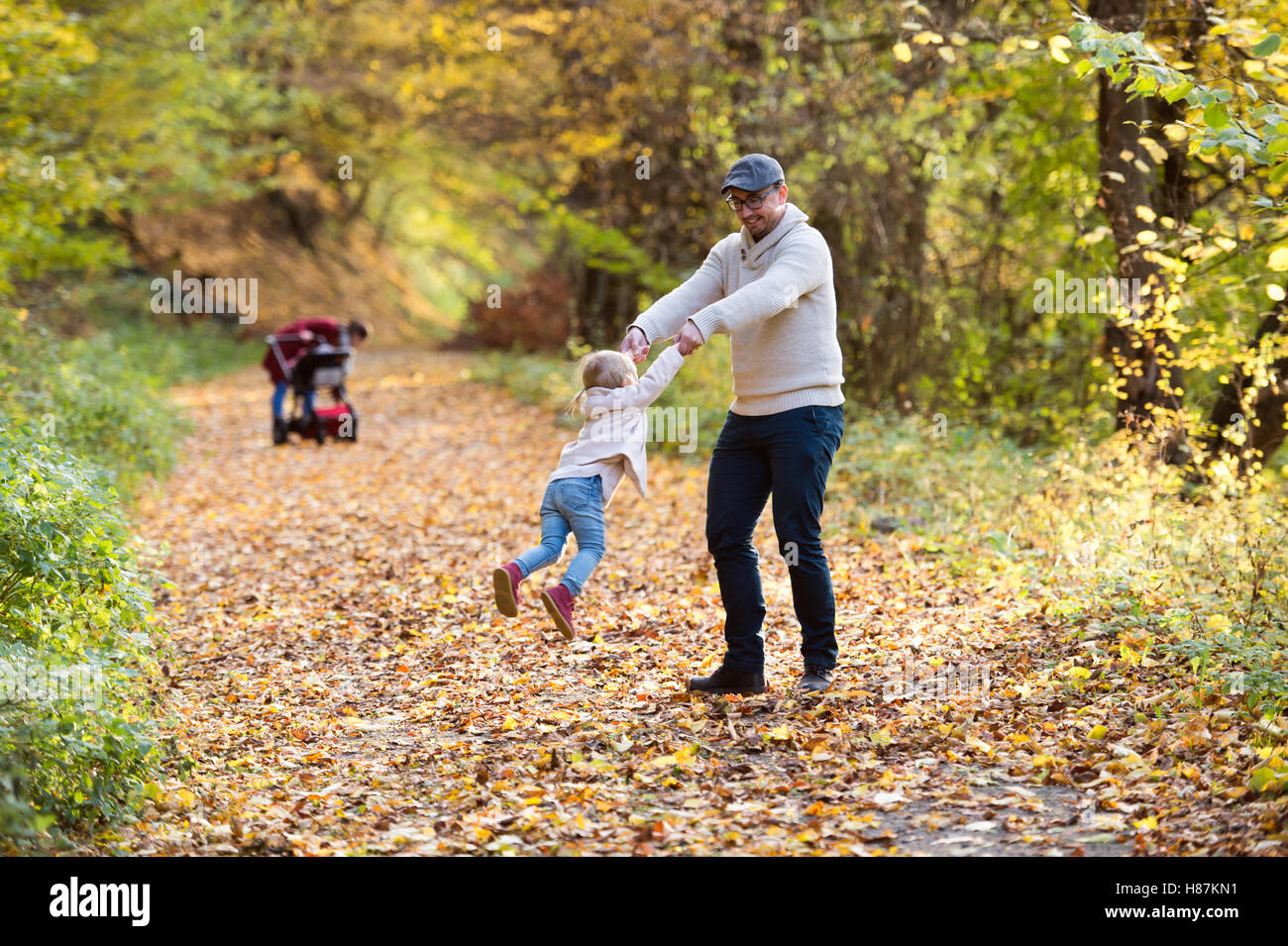 Beautiful young family on a walk in autumn forest Stock Photo - Alamy
