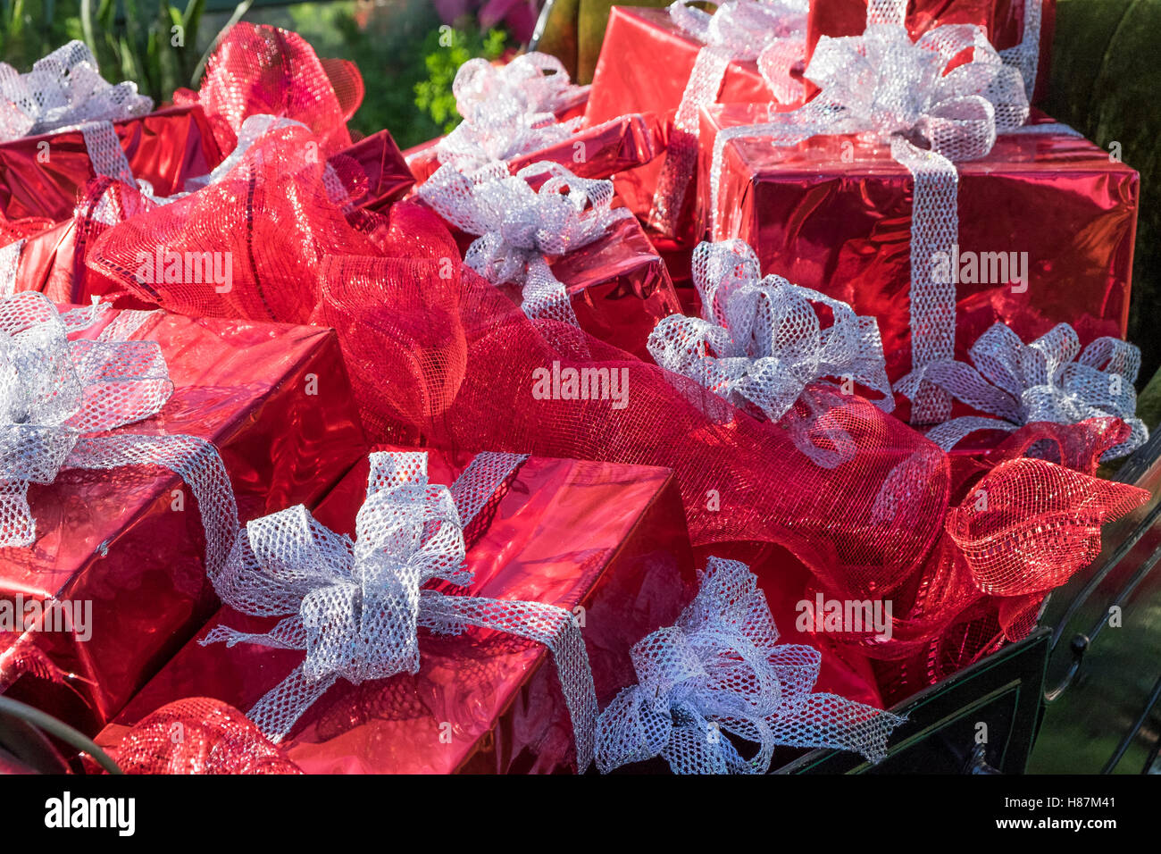 Presents wrapped with shiny red foil paper and silver ribbons tied in ...