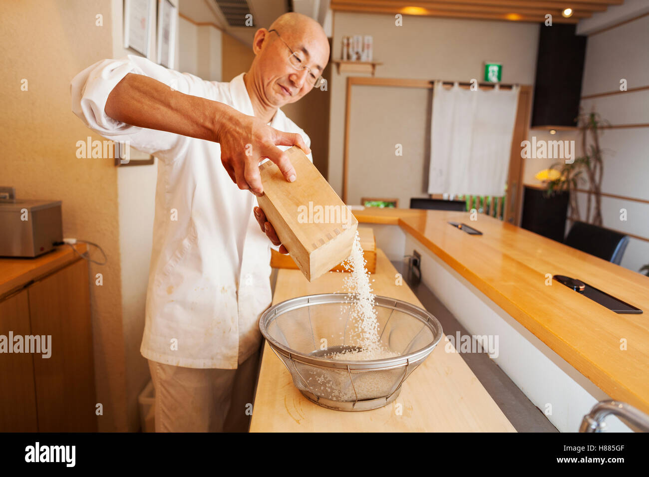 A chef working in a small commercial kitchen, an itamae or master sushi ...