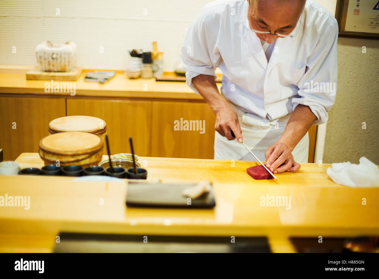 A chef working in a small commercial kitchen, an itamae or master chef ...