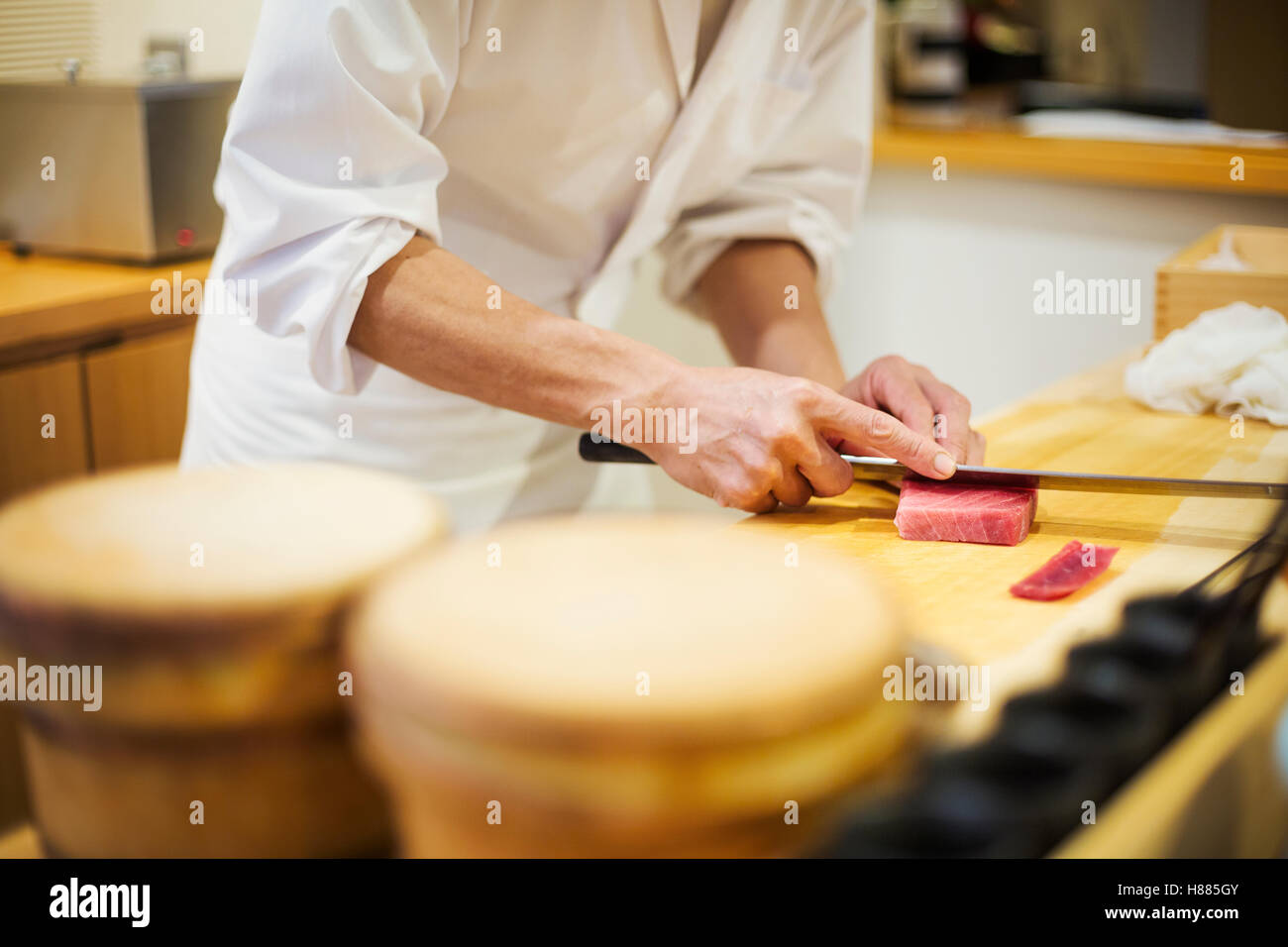 A chef working in a small commercial kitchen, an itamae or master chef ...