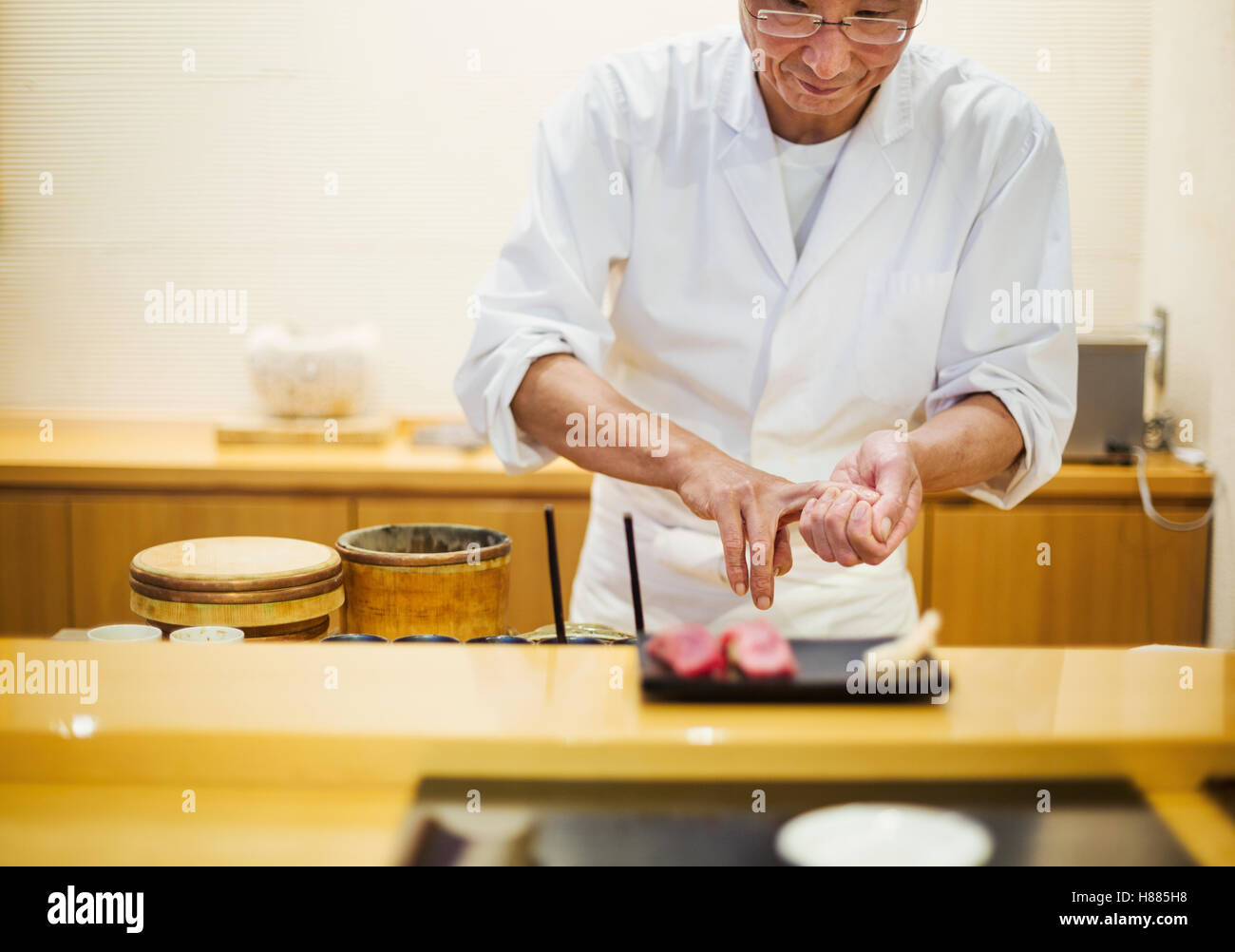 A chef working in a small commercial kitchen, an itamae or master chef ...