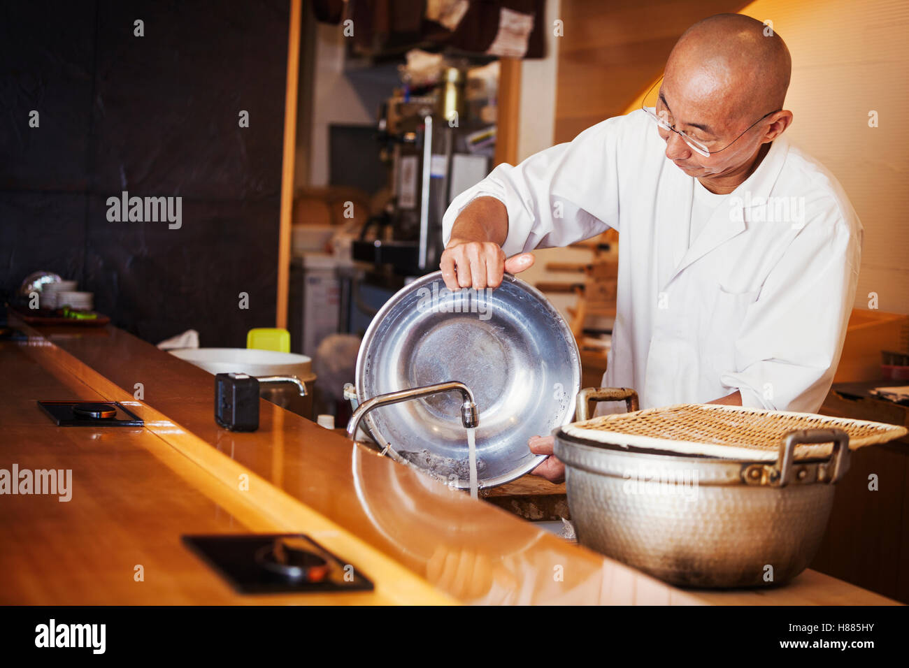 A chef working in a small commercial kitchen, an itamae or master chef ...