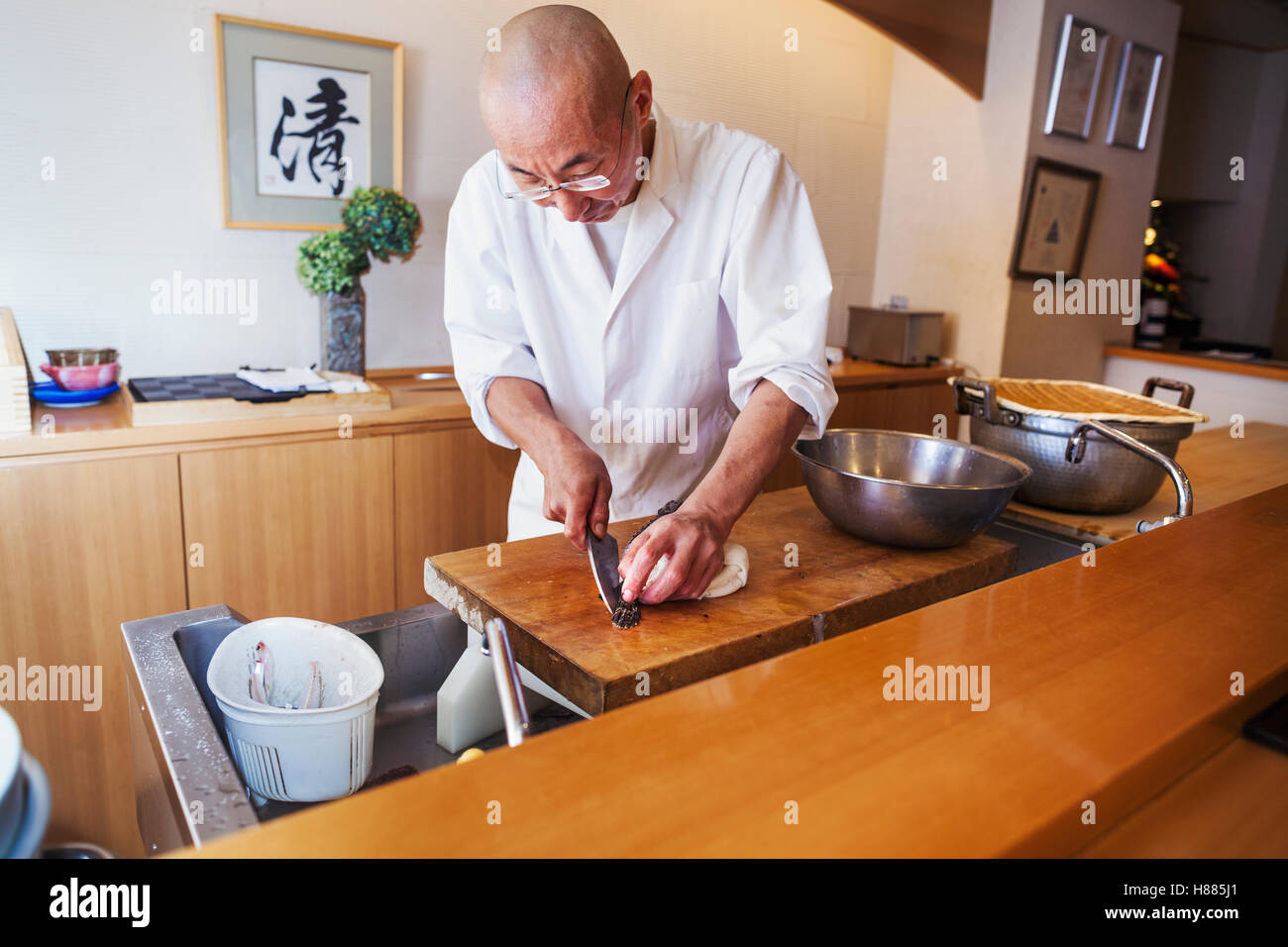 A chef working in a small commercial kitchen, an itamae or master chef ...