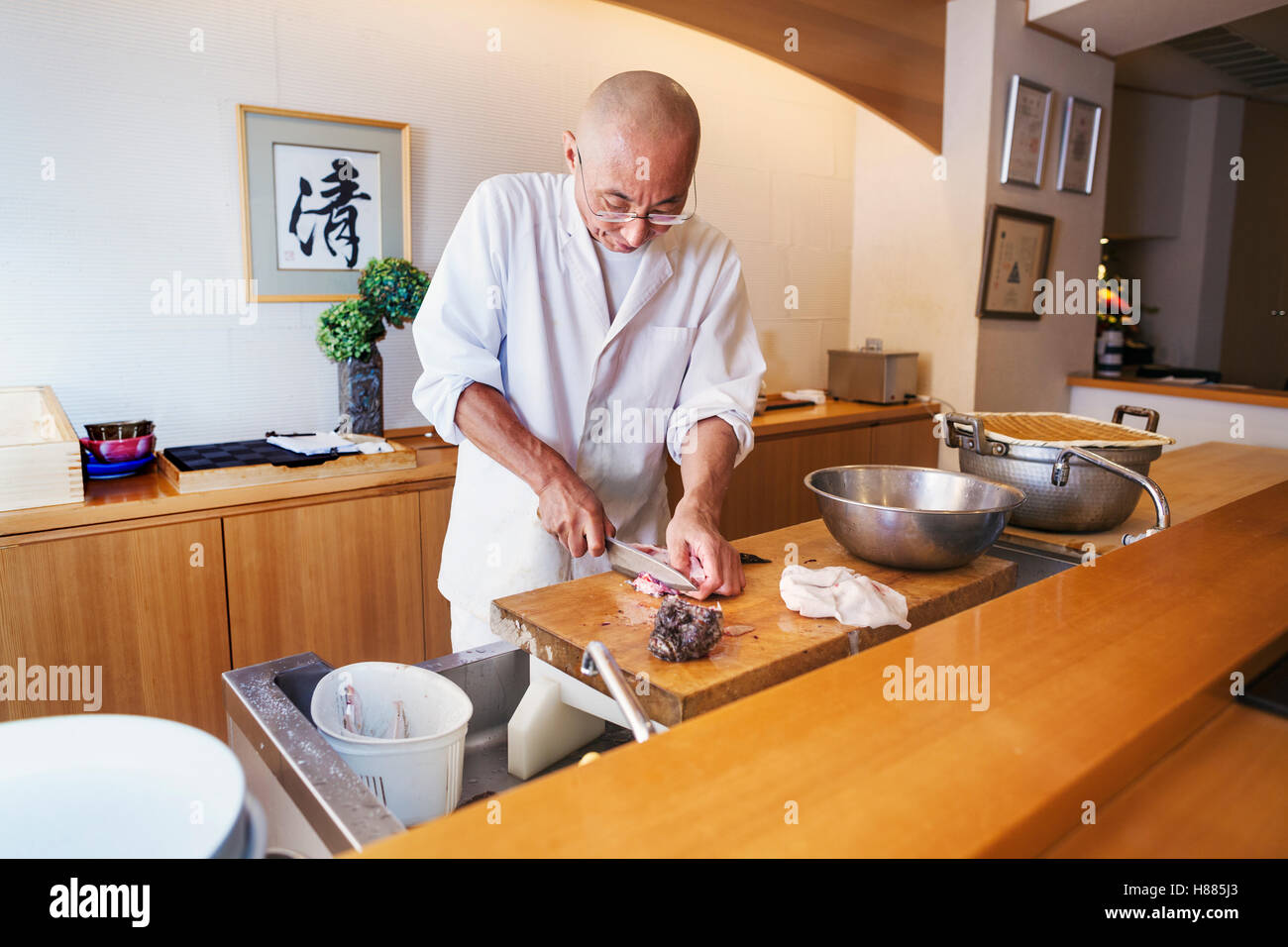 A chef working in a small commercial kitchen, an itamae or master chef ...