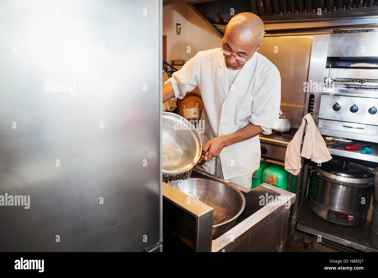A chef working in a small commercial kitchen, an itamae or master chef ...
