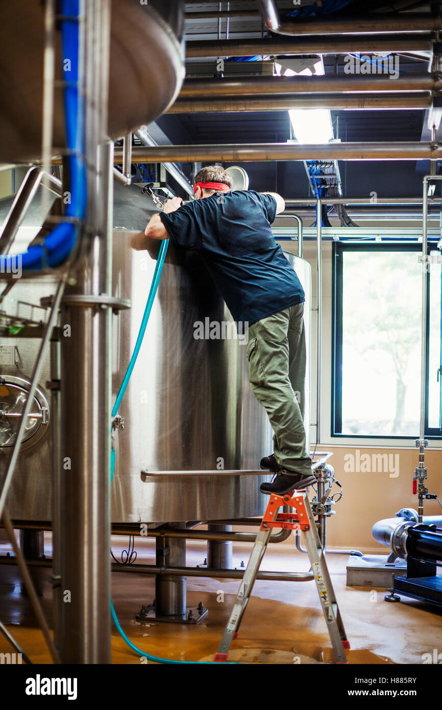 Man working in a brewery adjusting and checking the machinery which ...