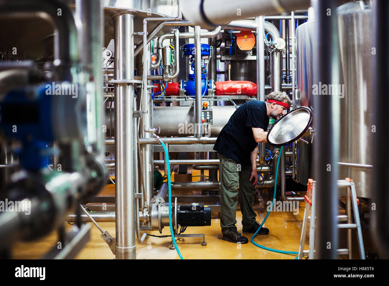 Man working in a brewery adjusting and checking the machinery which ...