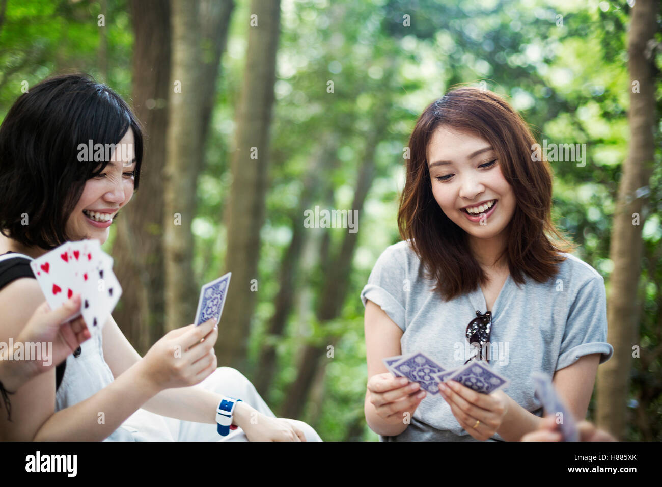 Two young women sitting in a forest, playing cards Stock Photo - Alamy