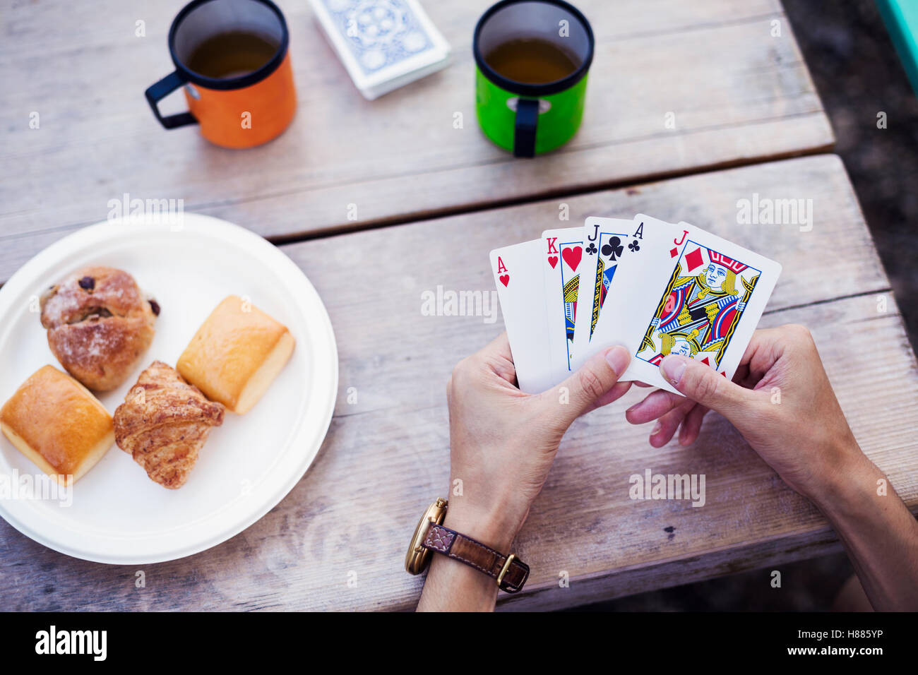 Close up of a man sitting at a table, holding playing cards Stock Photo ...