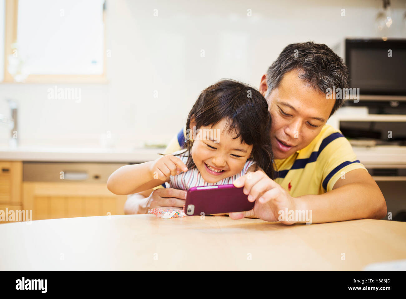 Family home. A man showing his daughter the smart phone screen Stock ...