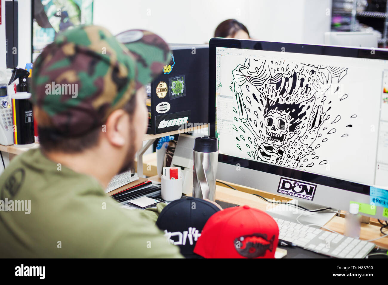 Design Studio. A man seated at a desk using a computer to design tee ...