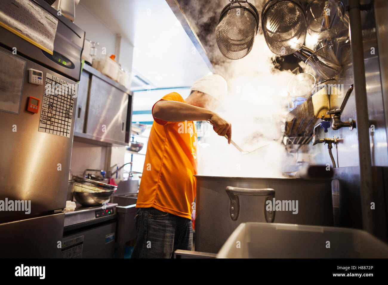 The ramen noodle shop kitchen. A vast pot on the stove, and steam ...