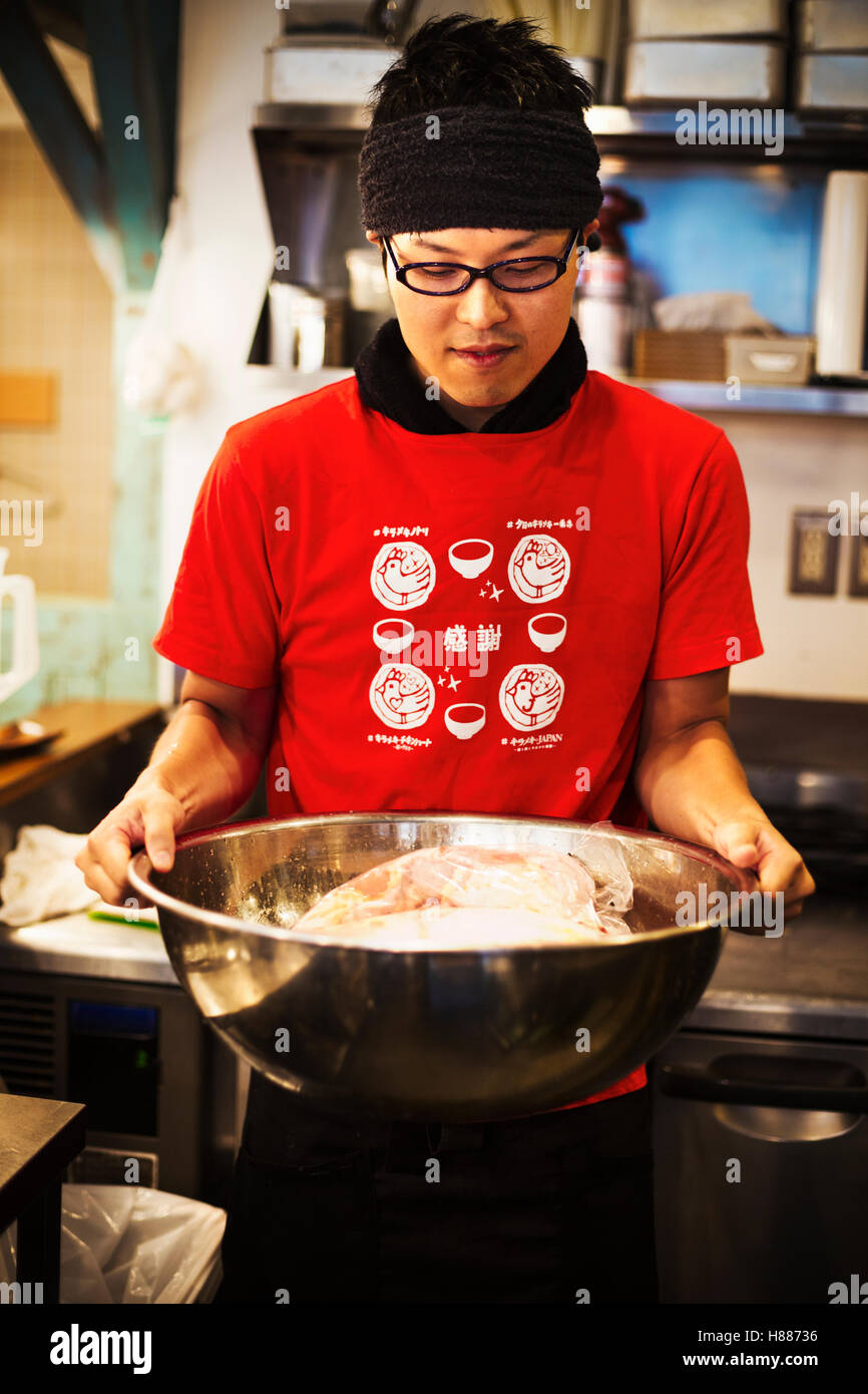 The ramen noodle shop. A chef preparing a huge metal bowl of broth with ...