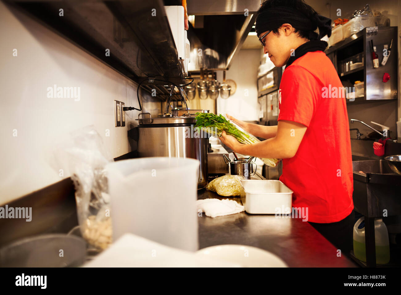 The ramen noodle shop. A chef working in a kitchen preparing food using ...