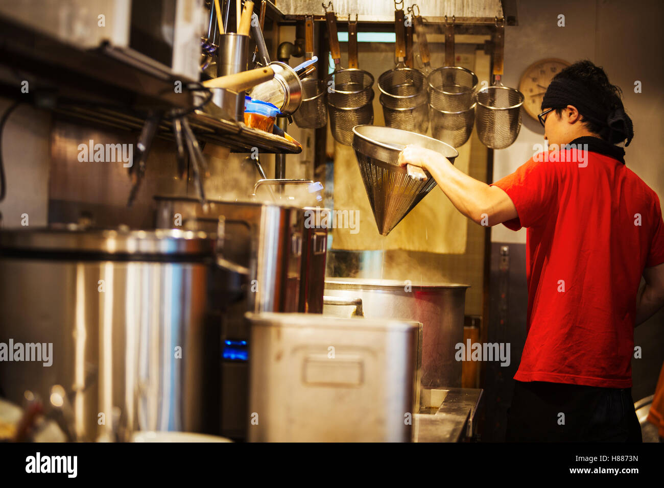 The ramen noodle shop. A chef working in a kitchen preparing food using ...