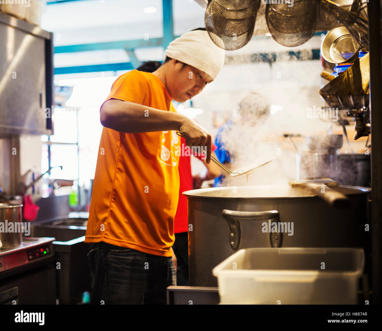 The ramen noodle shop. Staff preparing food in a steam filled kitchen ...