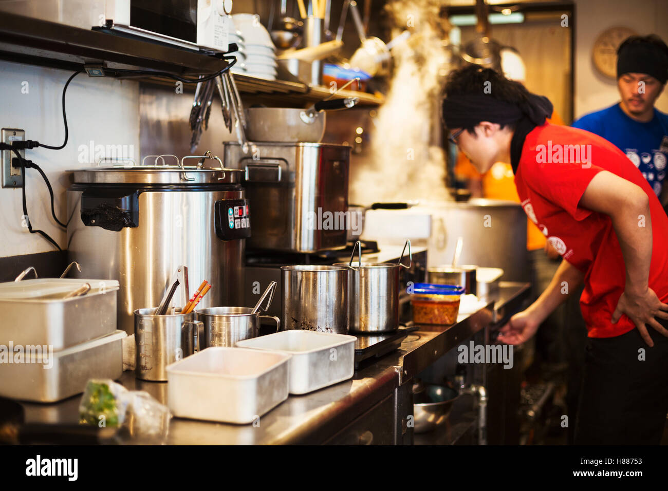 The ramen noodle shop. Staff preparing food in a tiny kitchen Stock ...