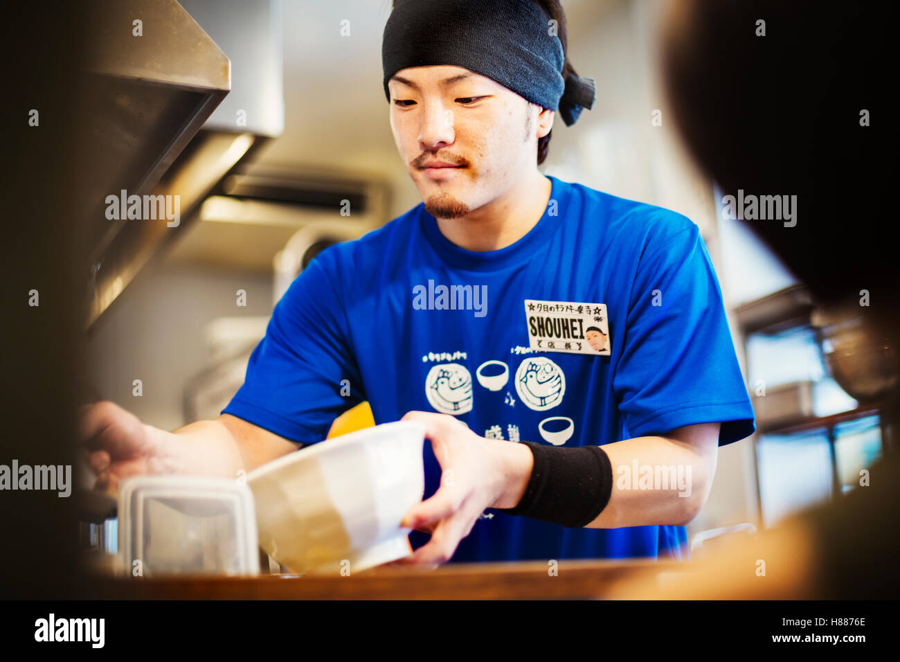 A ramen noodle shop kitchen. A chef preparing bowls of ramen noodles in ...