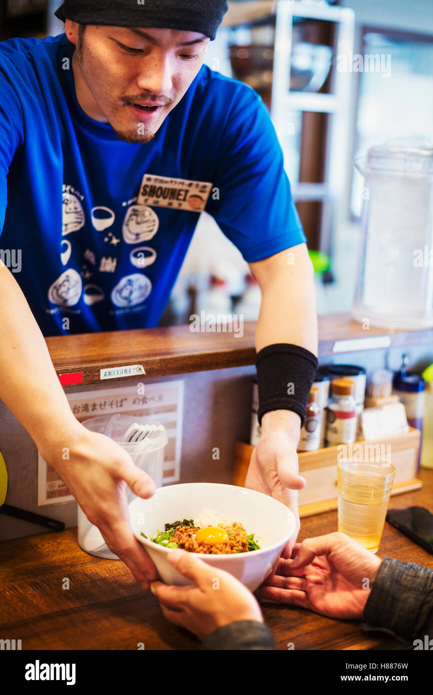 The ramen noodle shop. A chef delivering a bowl of ramen noodles to a ...