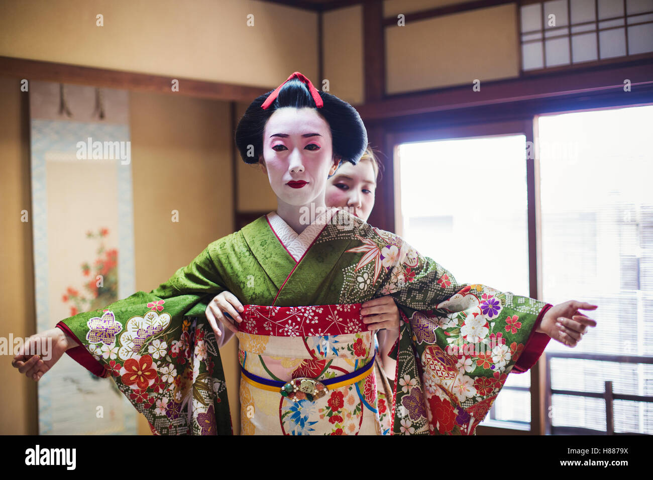 A woman being dressed in the traditional geisha style, wearing a kimono ...
