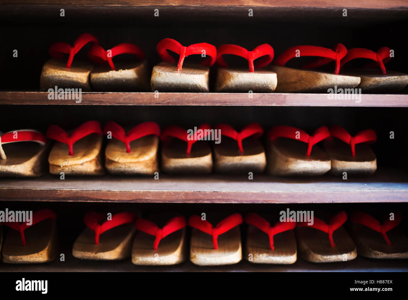 Rows of traditional wooden sandals with thick soles and red straps worn ...