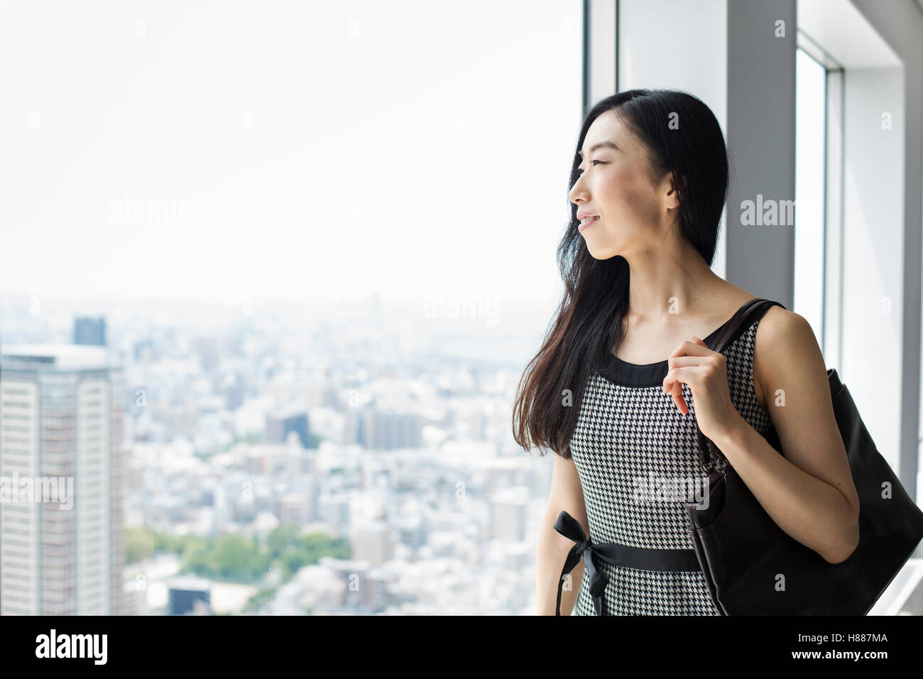 A business woman by a window with a view over the city Stock Photo - Alamy