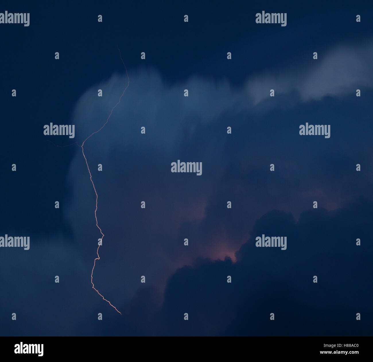 Single strike of lighting as a thunder storm rises at night Stock Photo ...