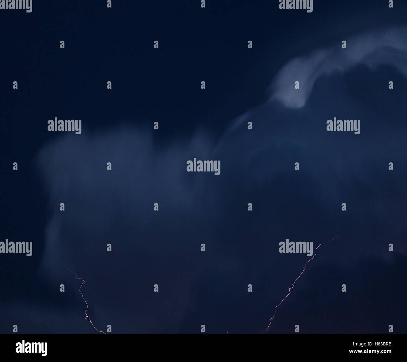 Two lightning strikes in the distance in front of a storm Stock Photo ...