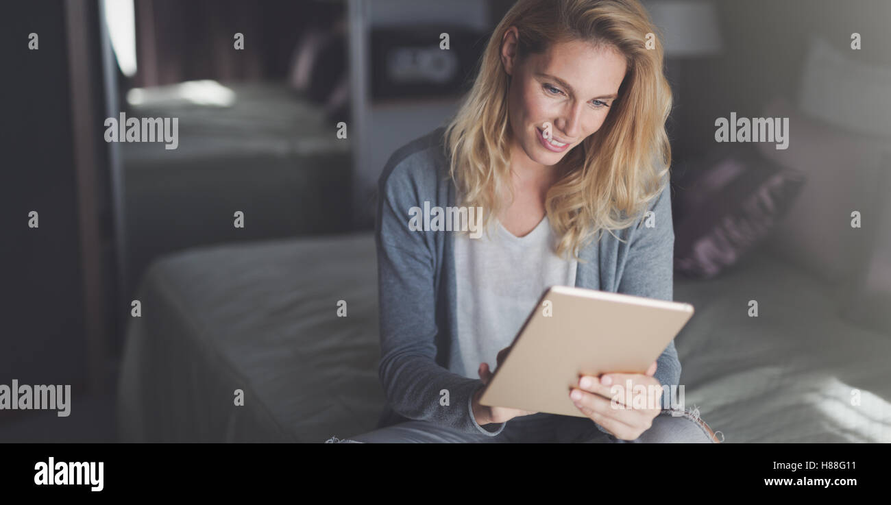 Beautiful blond woman using tablet at home Stock Photo - Alamy
