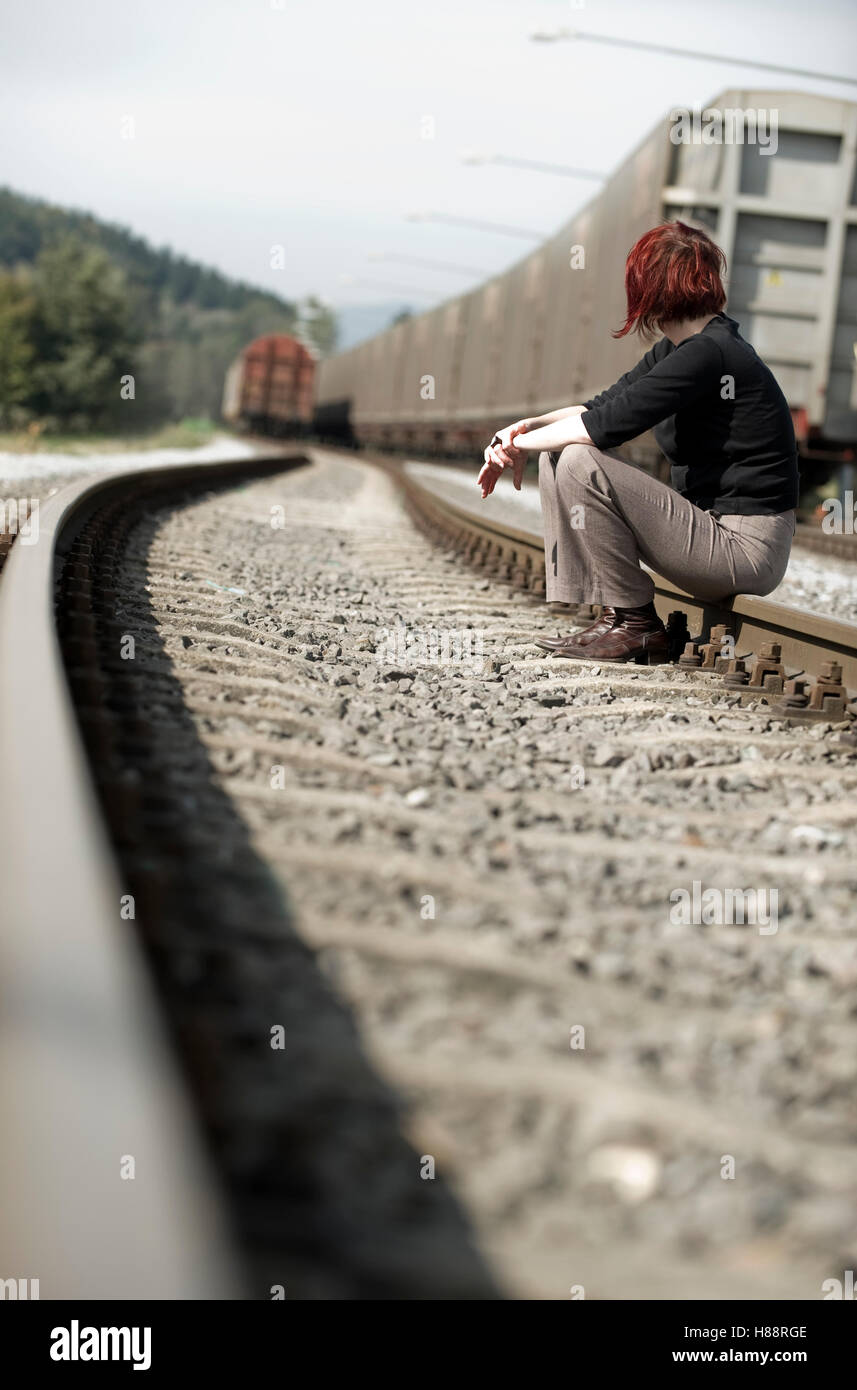 Young woman sitting on a railway track Stock Photo - Alamy