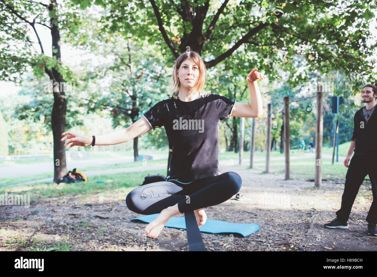 Woman balancing a tightrope or slackline outdoor in a city park in ...