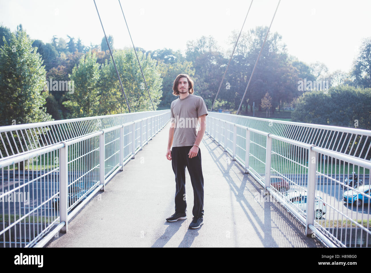 Young beautiful caucasian man standing on a bridge outdoor in back ...