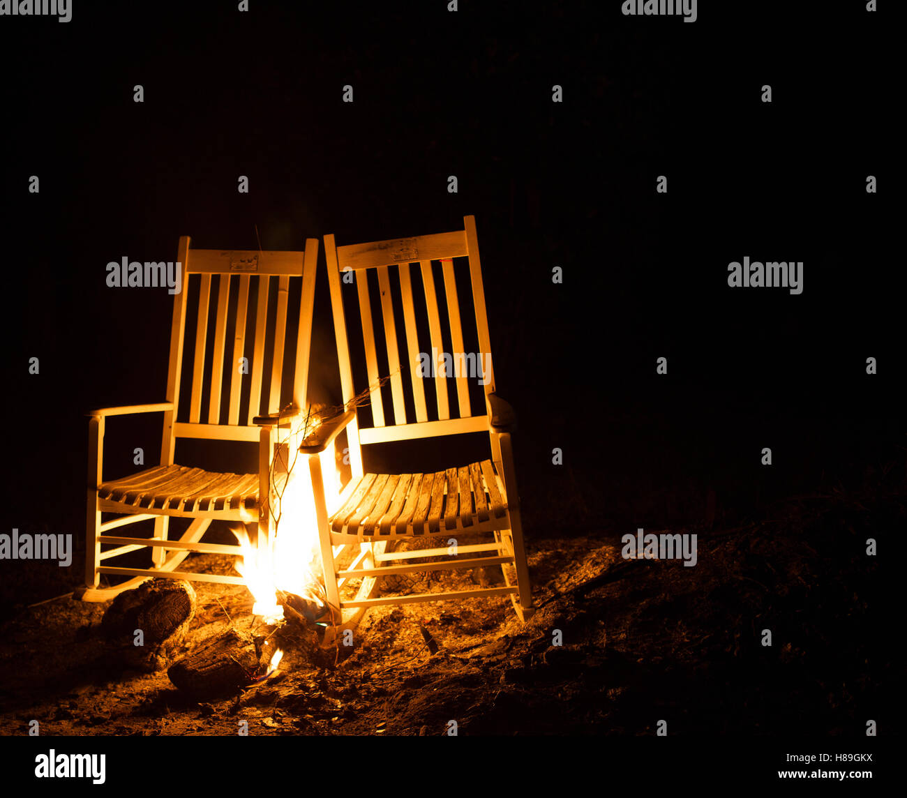 White rocking chairs with flames during the night Stock Photo - Alamy
