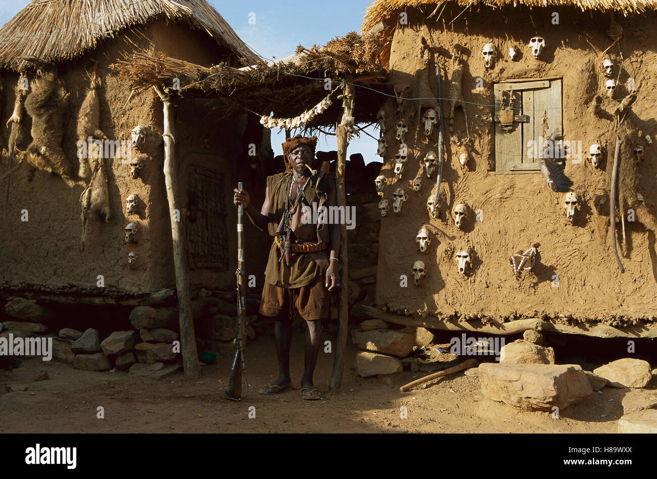 Dogon hunter in front of his hut showing various primate skulls, Sahel ...