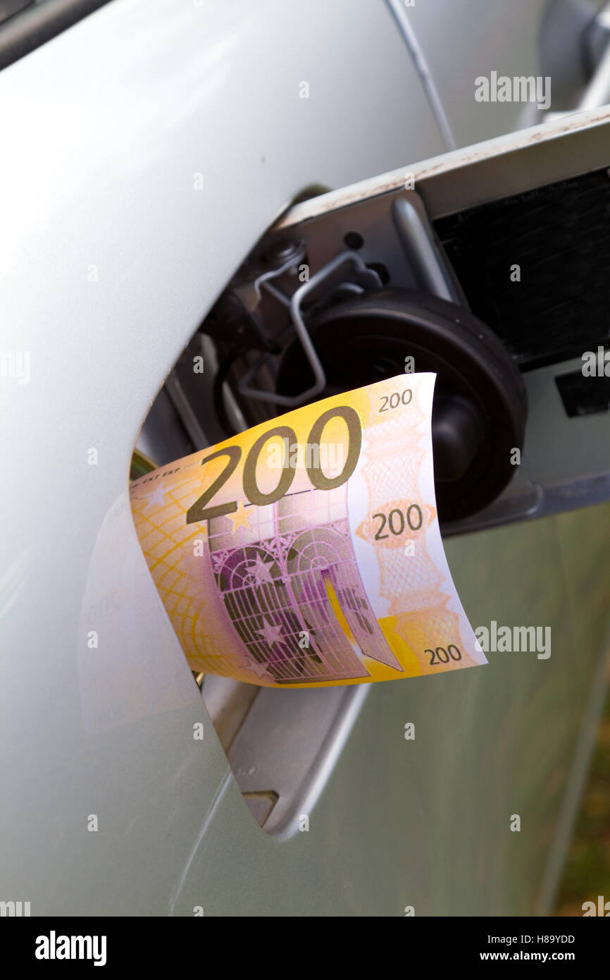 Rising gasoline prices concept money in gas tank Stock Photo - Alamy