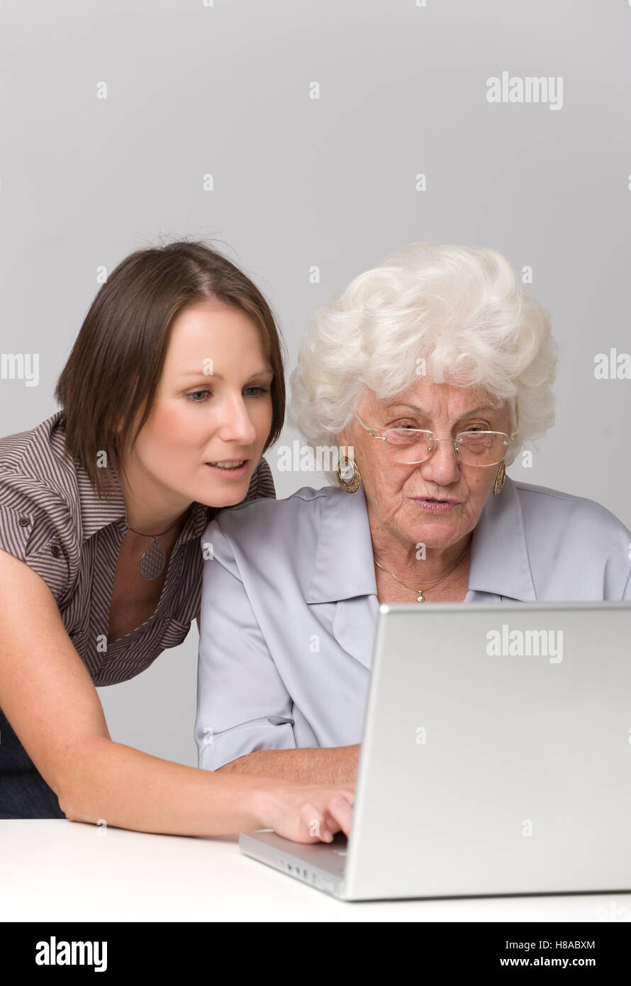 Young woman helping older woman using a laptopp Stock Photo - Alamy