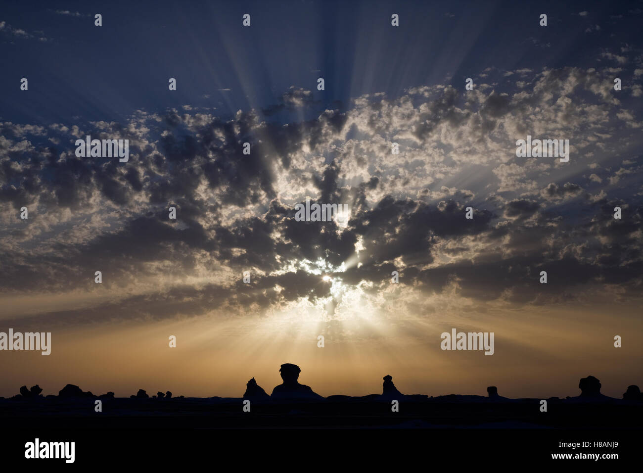 Sunrays shining through clouds at sunrise above limestone rock ...