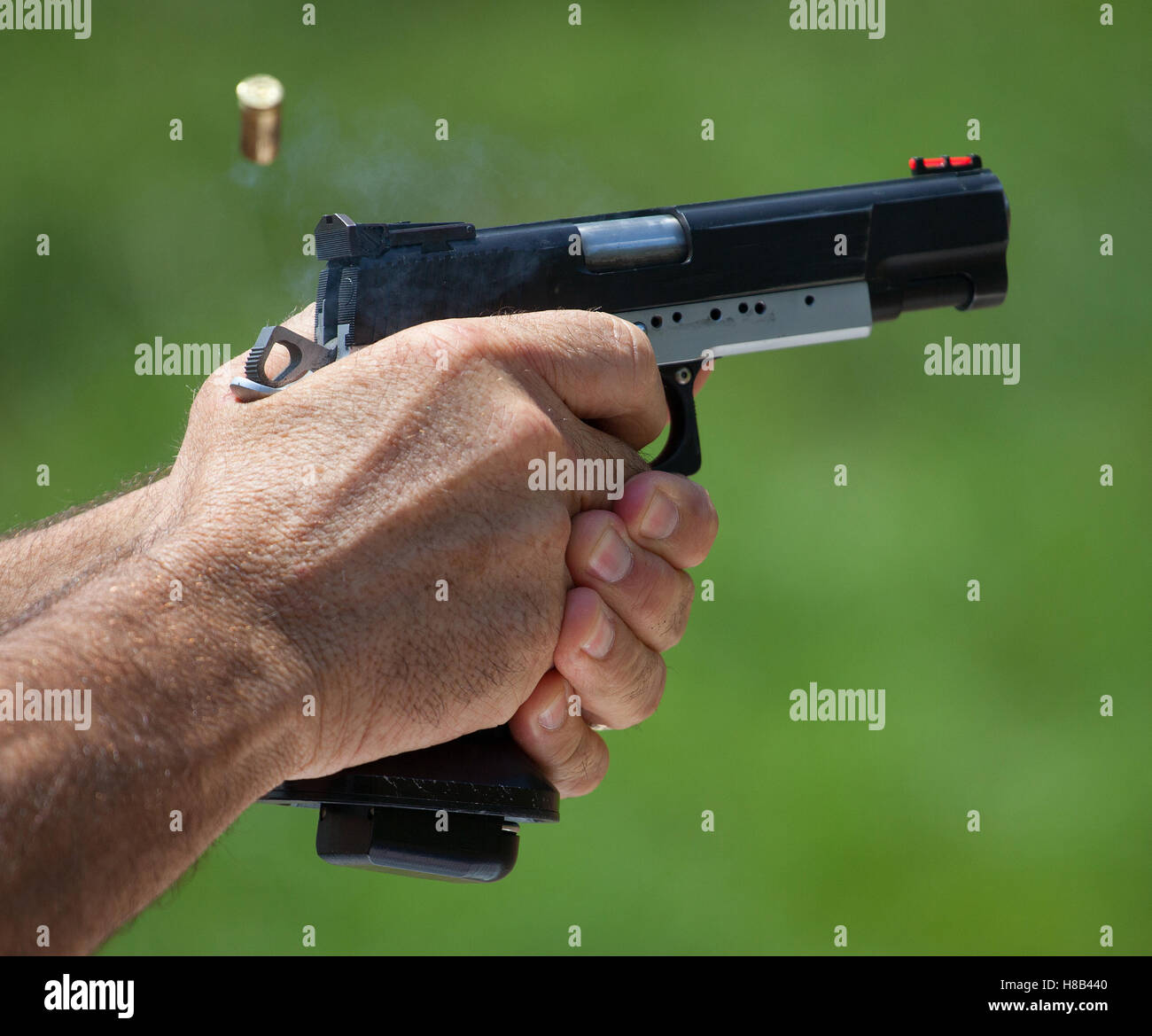 Handgun already ready to shoot again with brass flying Stock Photo - Alamy
